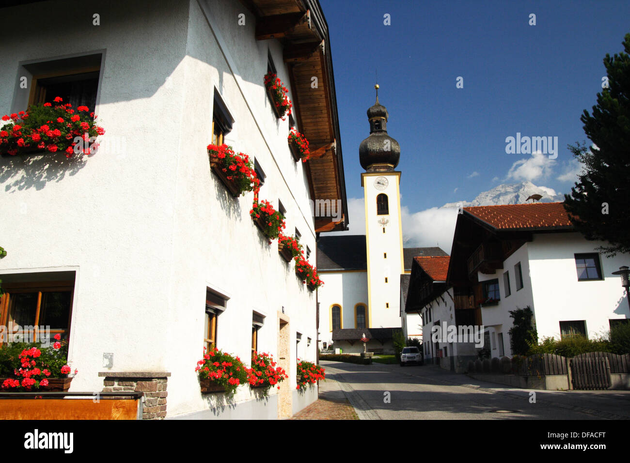 A Tyrolean village, blue sky with window boxes and a church with an ...