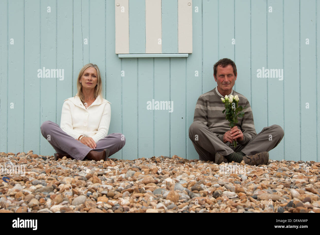 mature couple sitting apart on the beach, relationship breaking up ...
