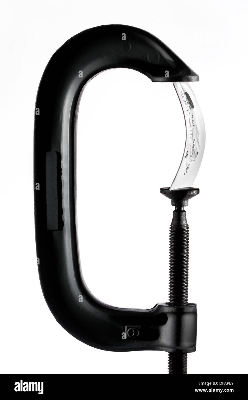 Credit / debit card being crushed by large black C clamp, isolated on a ...