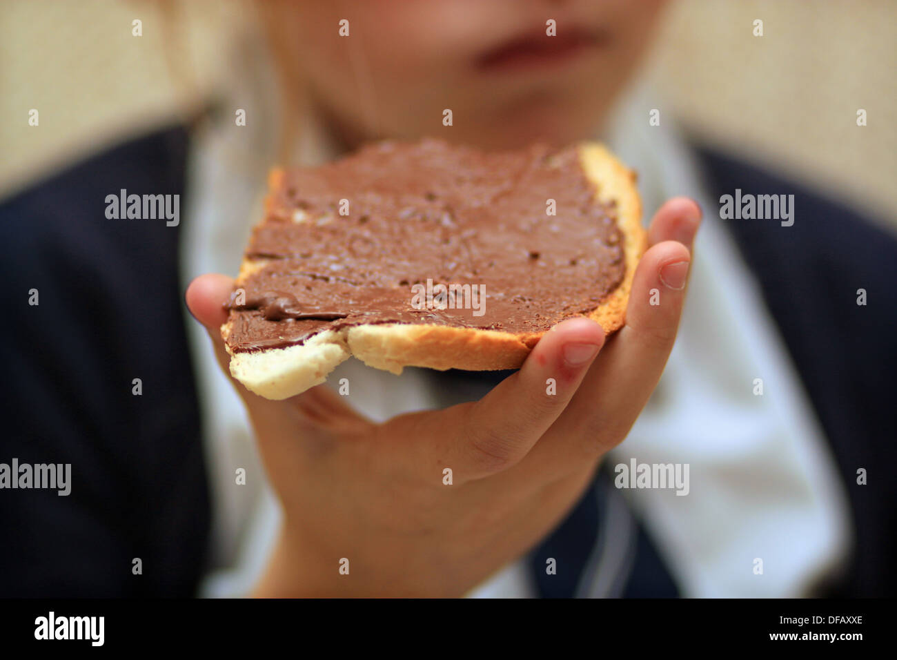 Young girl eating a slice of toast with chocolate spread Stock Photo ...