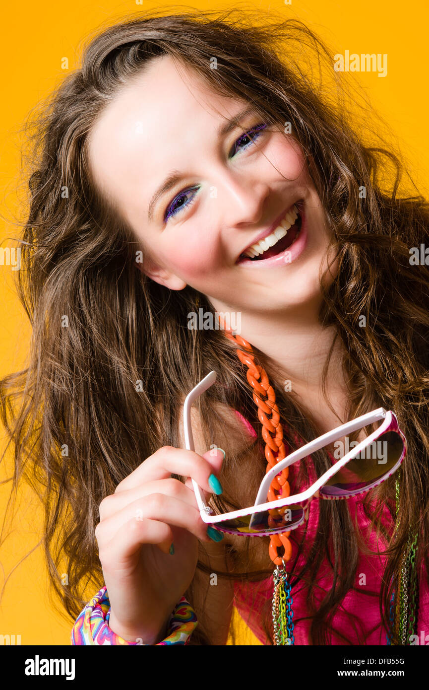 Beautiful girl wearing sunglasses, expressing faces, yellow background ...