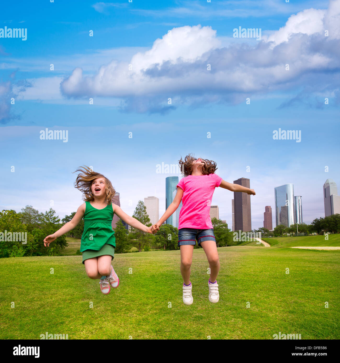 Two sister girls friends jumping happy holding hand in urban modern ...