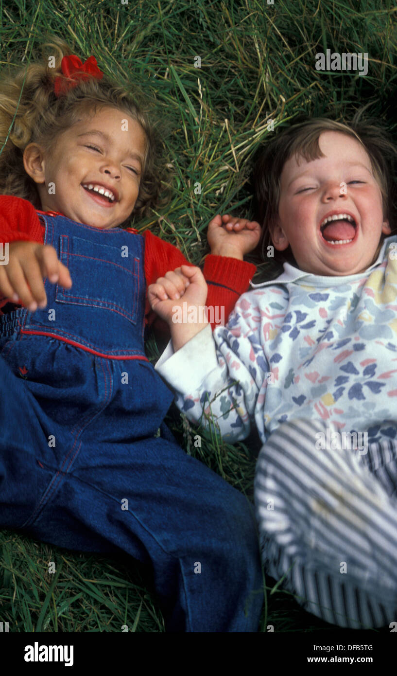two little girls rolling about on the grass laughing Stock Photo - Alamy