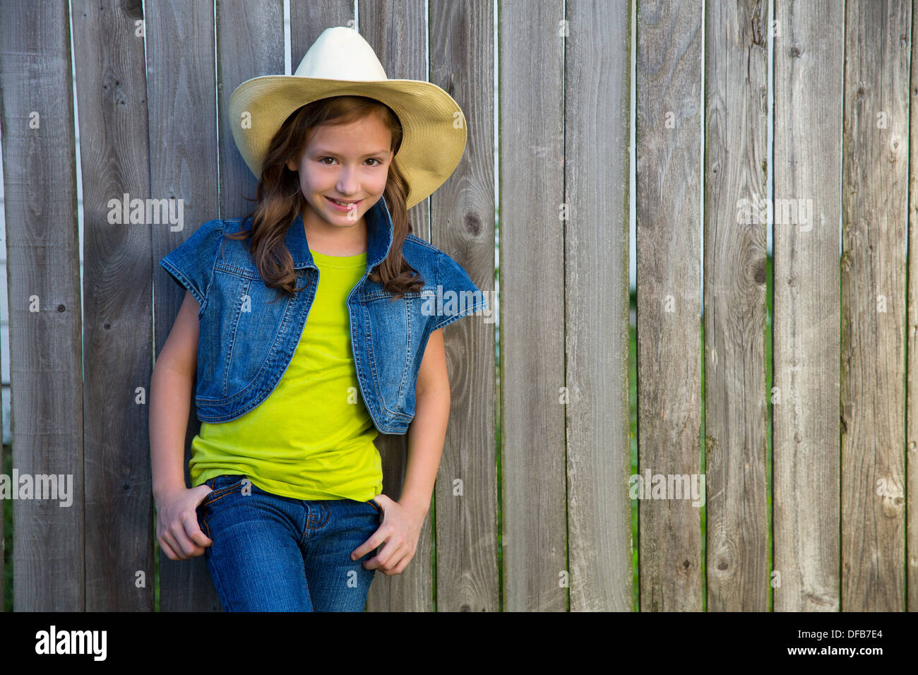 Children girl as kid cowboy girl cowgirl posing on wooden fence far ...