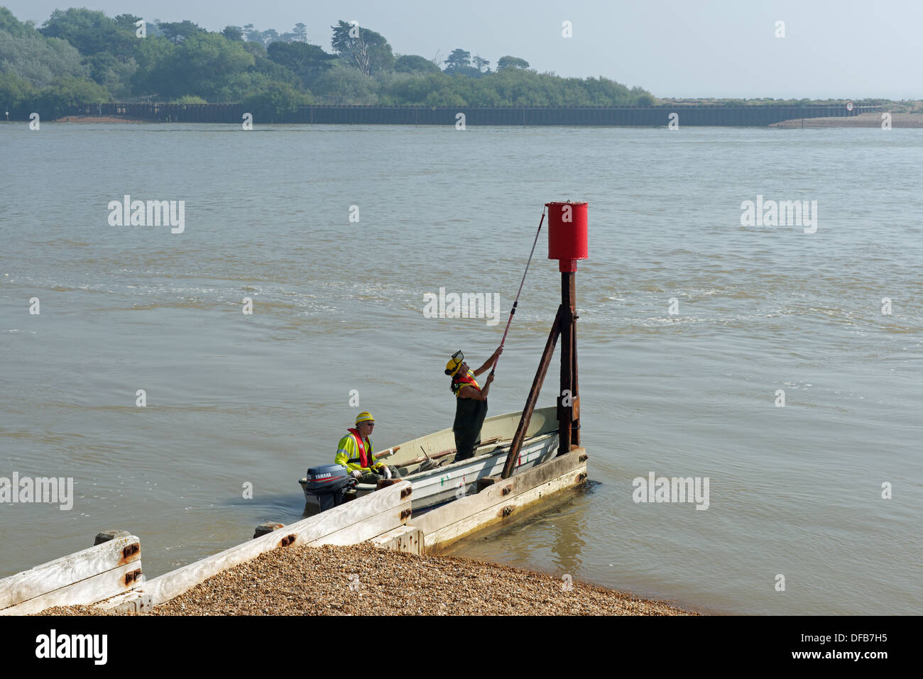 Groyne marker post being painted, river Deben, Felixstowe Ferry ...