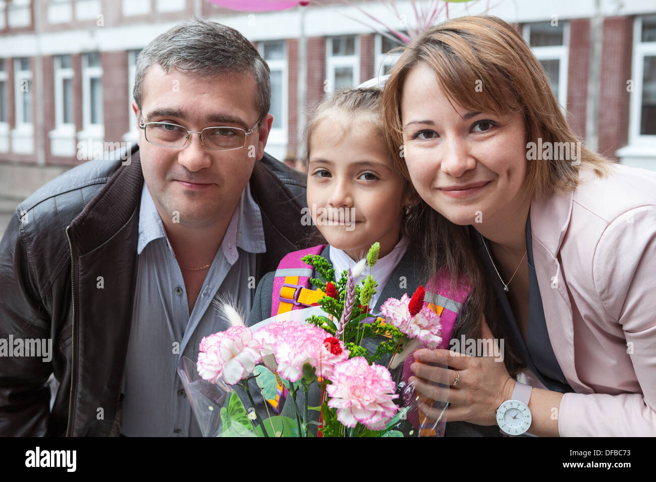 Happy parents portrait with first class school girl before entering ...