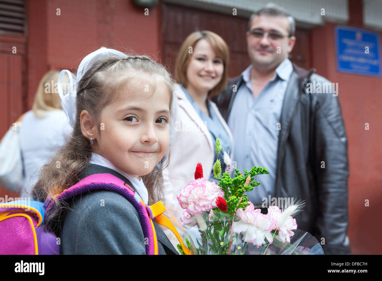 Happy parents standing together with smiling daughter going back to ...