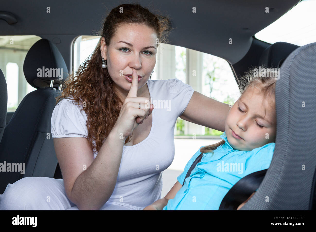 Mother showing shh gesture when child asleep in car Stock Photo - Alamy