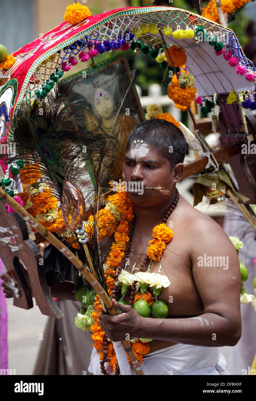 A Hindu devotee with his cheeks pierced with a metal skewer carries a ...