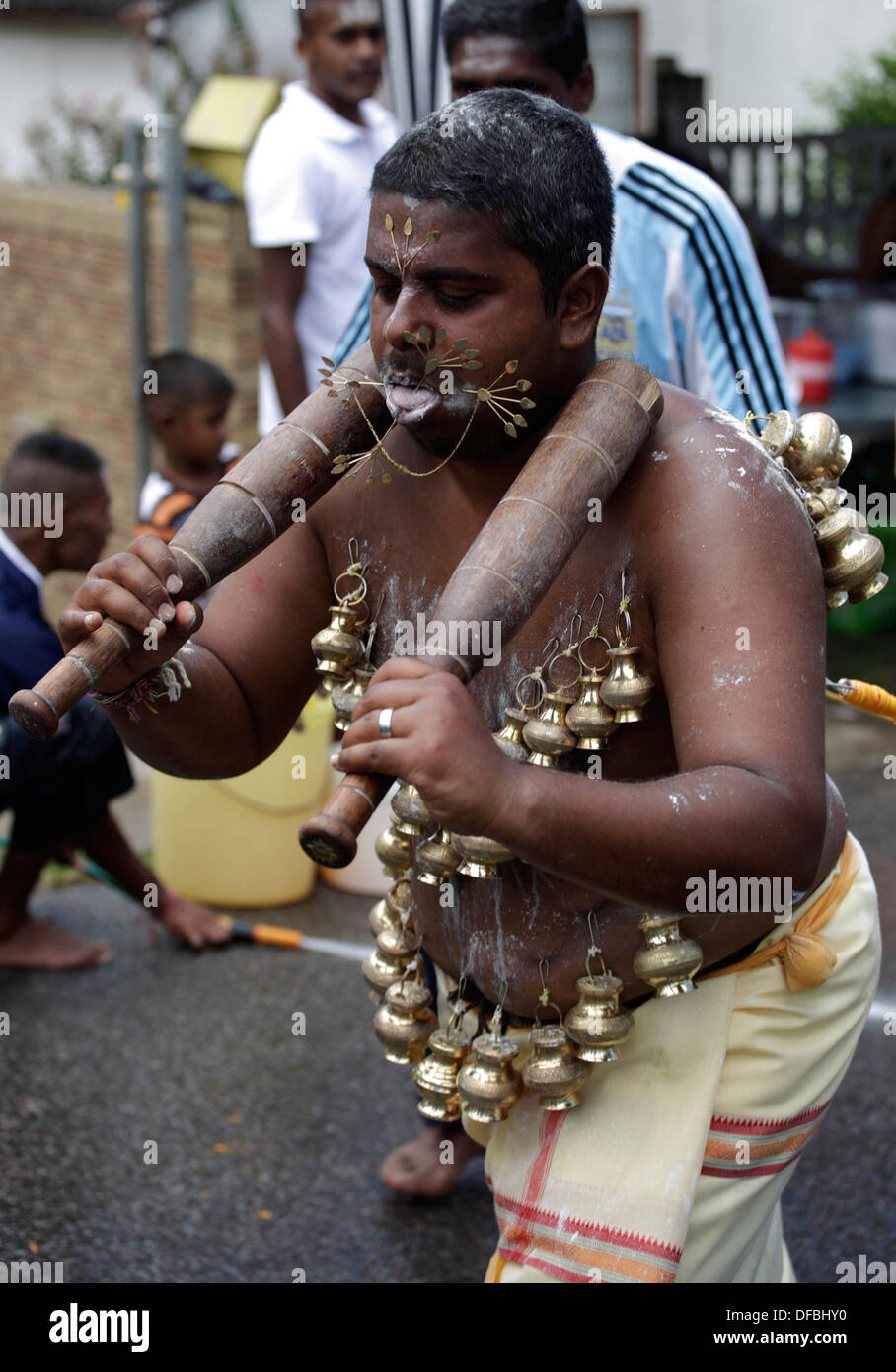 A Hindu devotee with his cheeks pierced with a metal skewer carries a ...