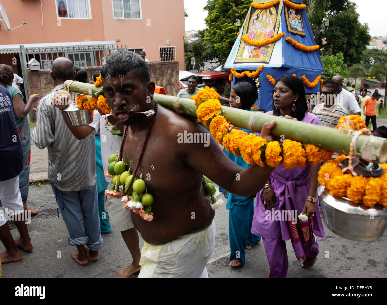 A Hindu devotee with his cheeks pierced with a metal skewer carries a ...