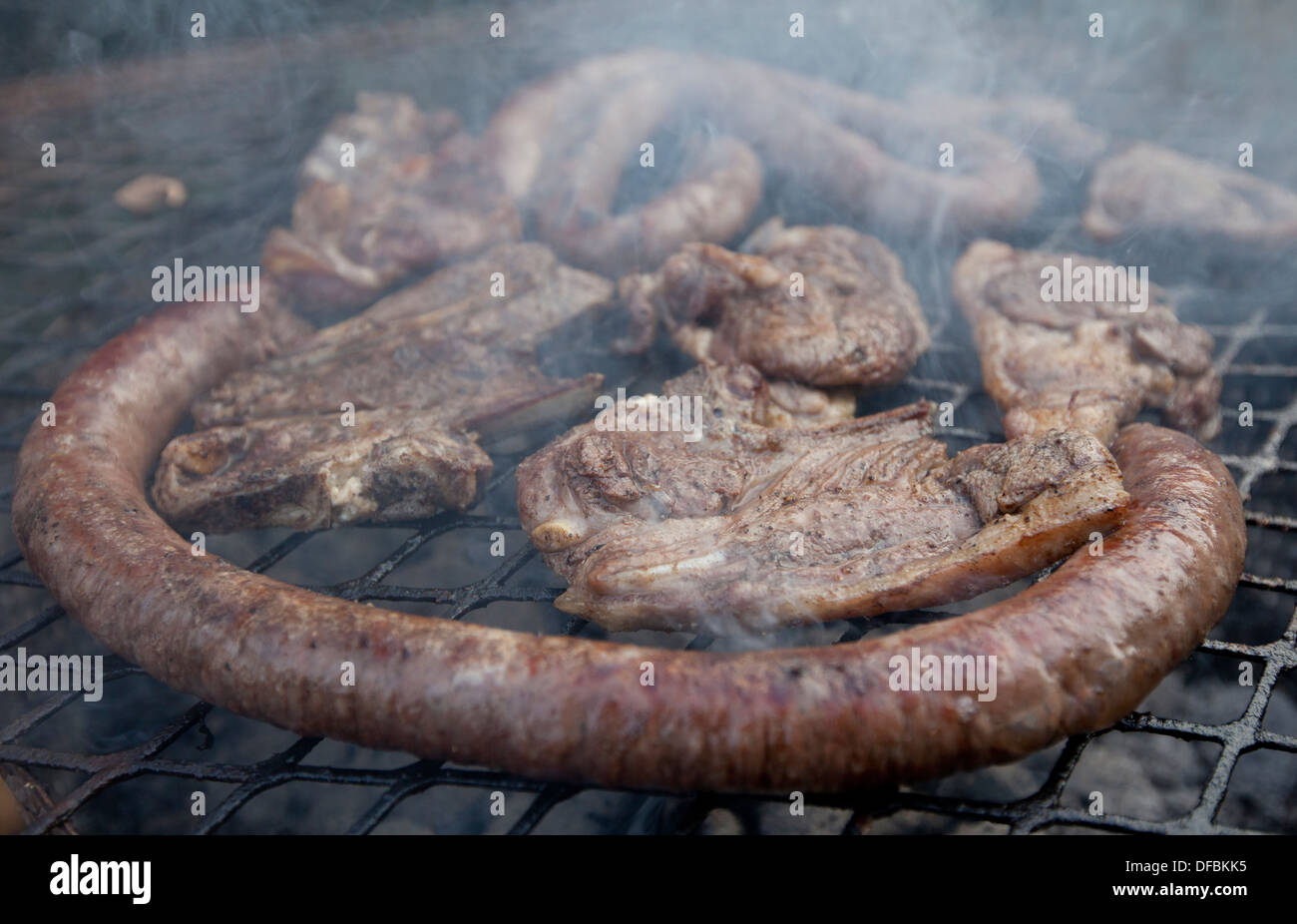 Boerewors and lamb chops are cooked on an open fire at a traditional ...