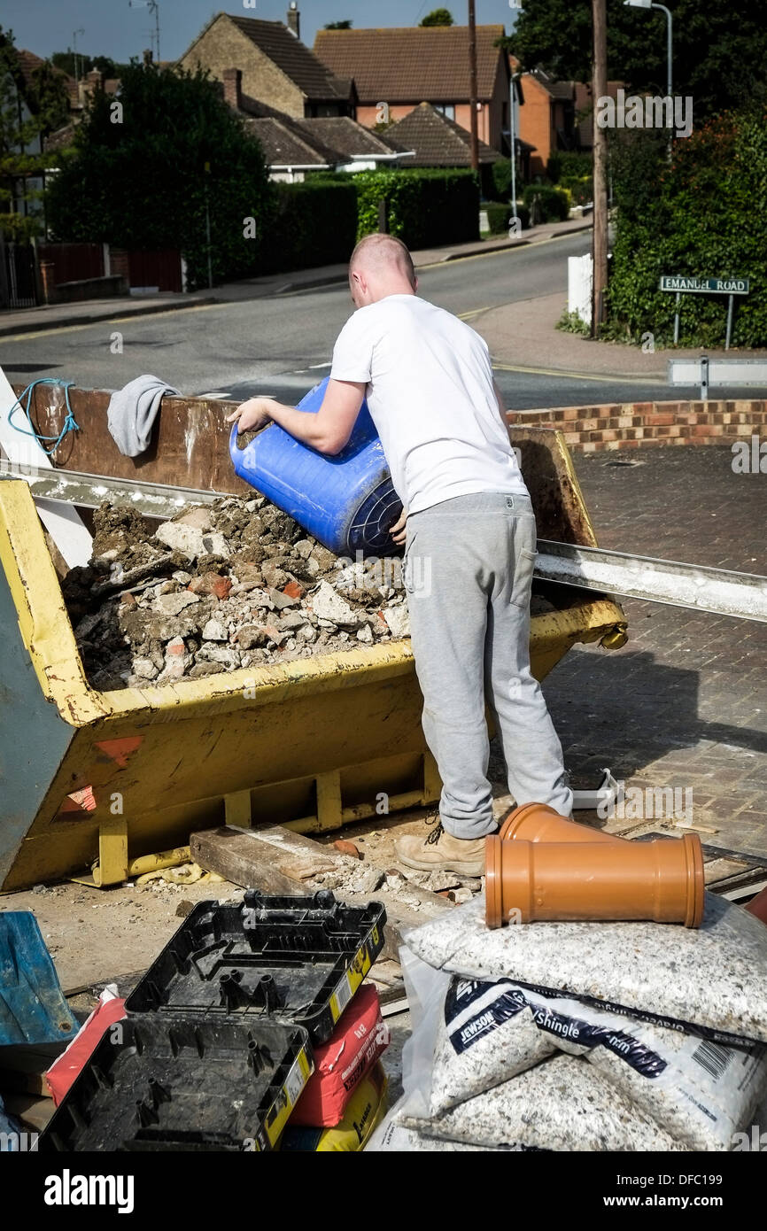 A construction worker emptying a bucket into a rubbish skip Stock Photo ...
