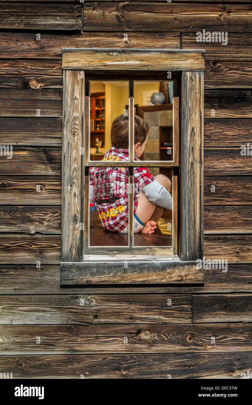 Three year old boy, in red and white checkered shirt, keenly watching ...