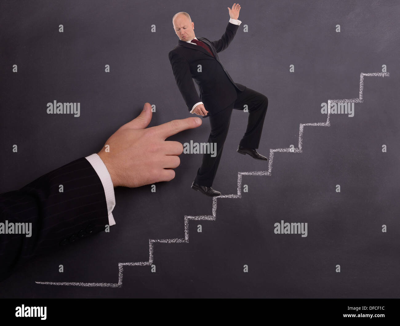 a businessman being pushed poked up stairs on a chalkboard background ...