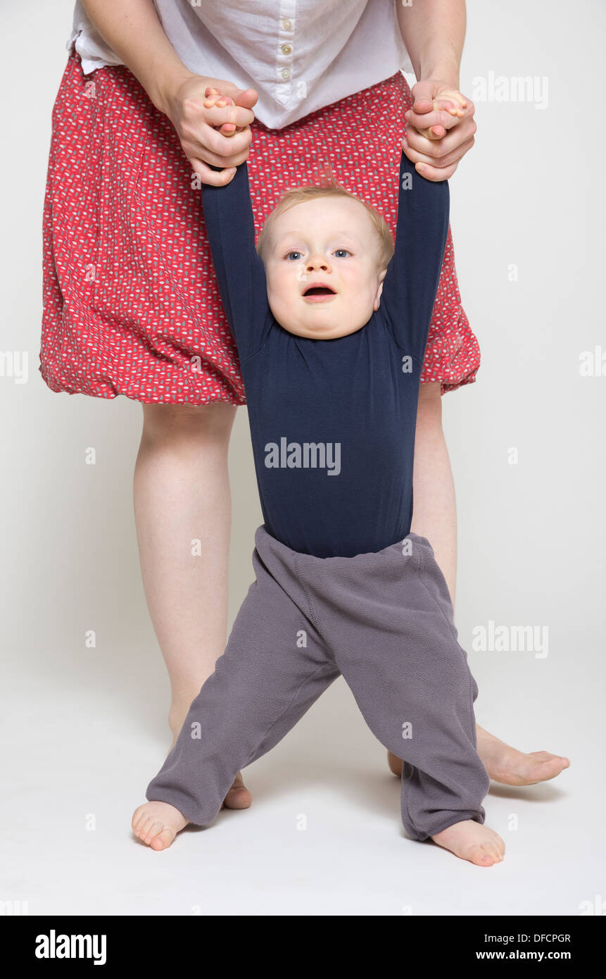 Mother helping baby boy to walk Stock Photo - Alamy