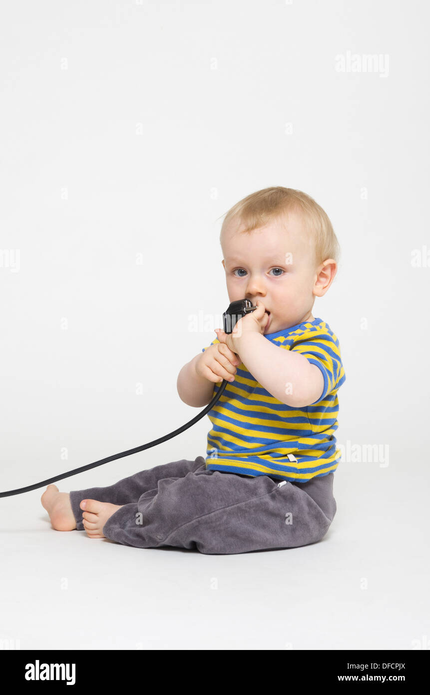 Portrait of baby boy holding electric plug Stock Photo - Alamy
