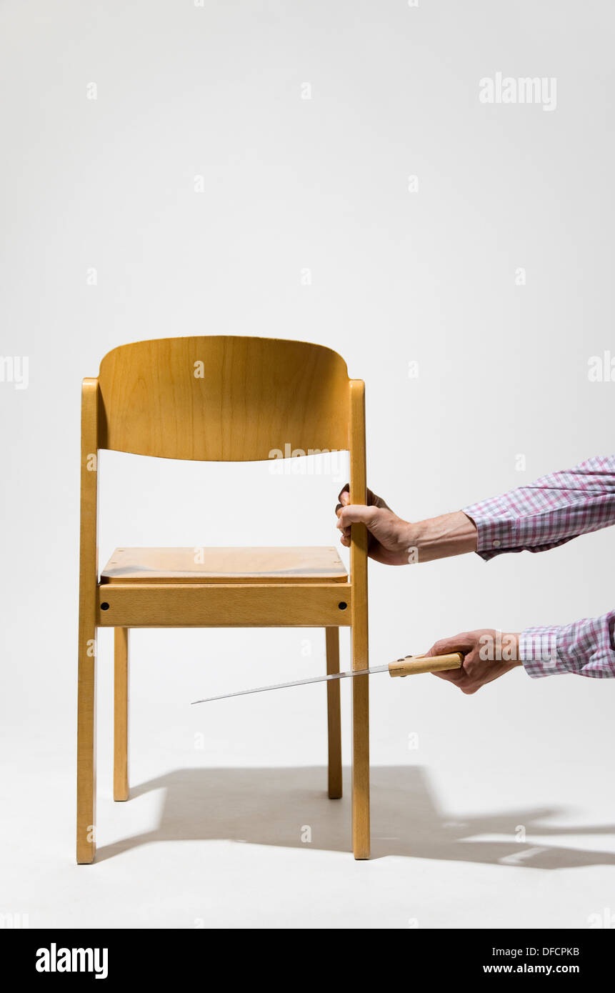 Mature man cutting chair with saw Stock Photo - Alamy