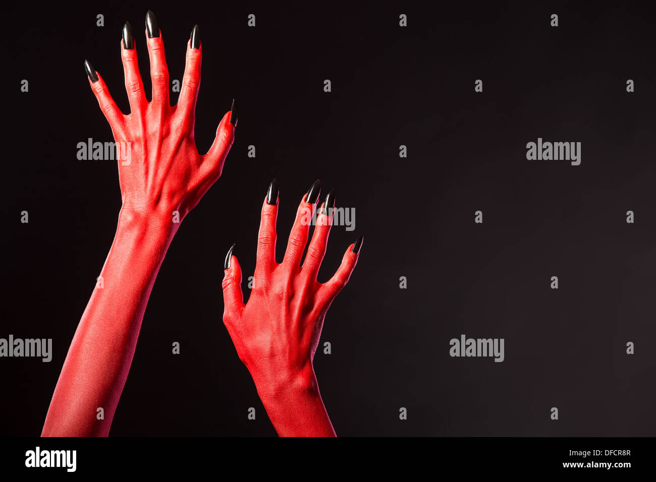 Red devil hands with black nails, Halloween theme, studio shot on black ...
