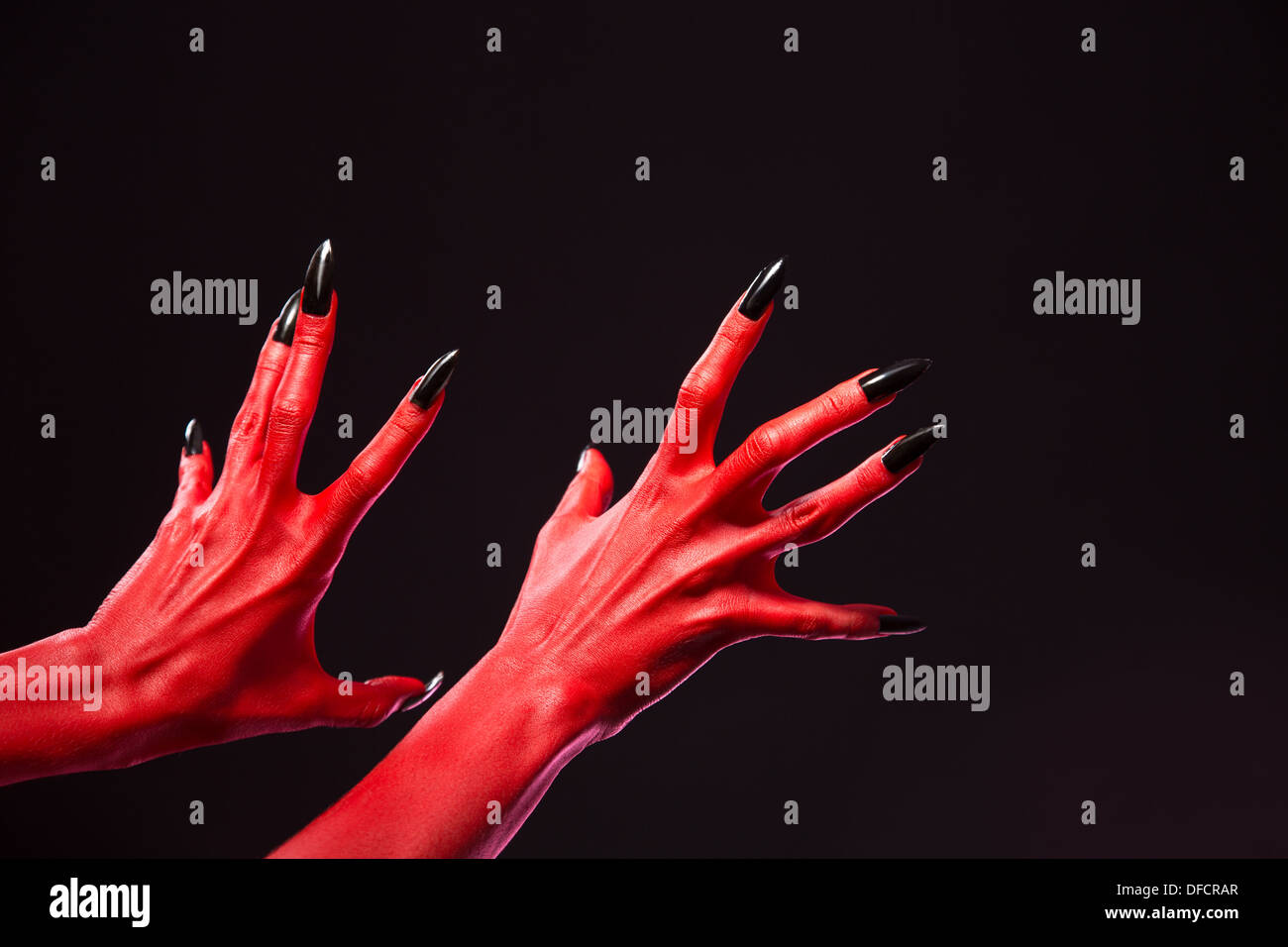 Spooky red devil hands with black nails, Halloween theme, studio shot ...