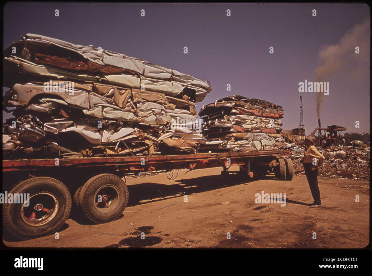 Compacted old cars are loaded on a flatbed truck, ready for shredding ...