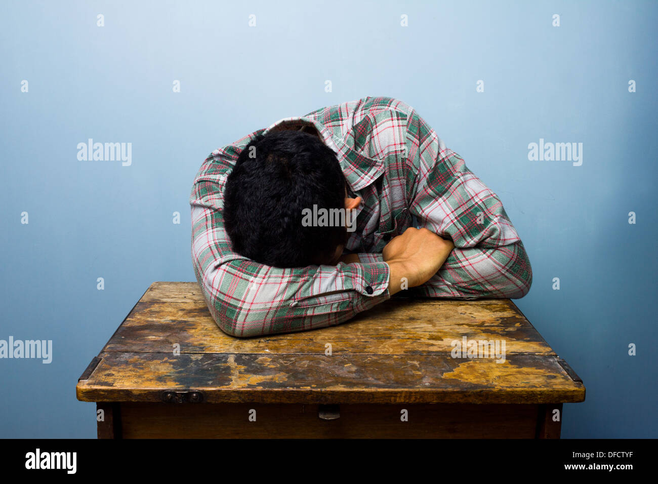 Sad man is sitting at an old school desk Stock Photo - Alamy