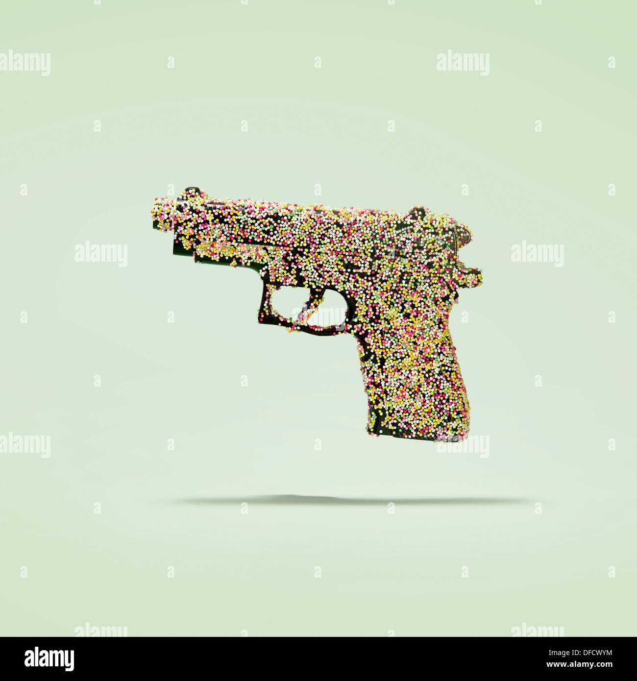 Candy covered hand gun on pastel green background Stock Photo - Alamy
