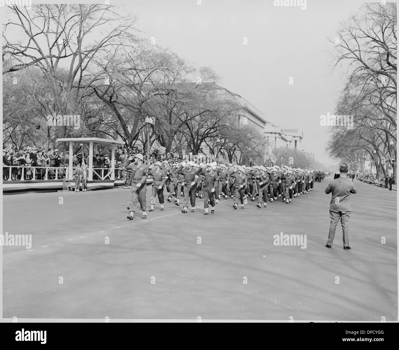 A distance view of President Harry S. Truman observing soldiers march ...