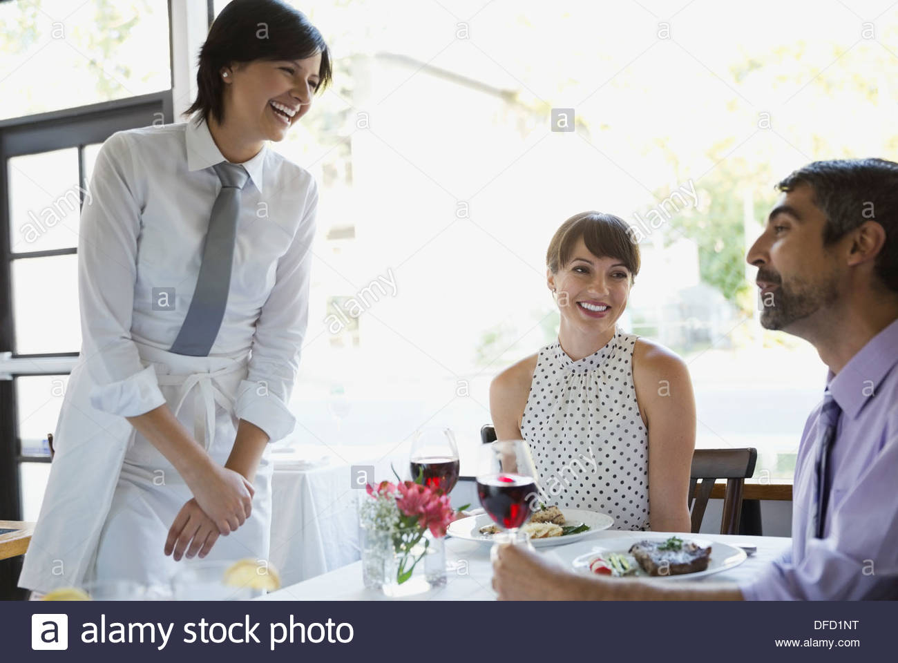 Happy waitress talking with couple in restaurant Stock Photo - Alamy