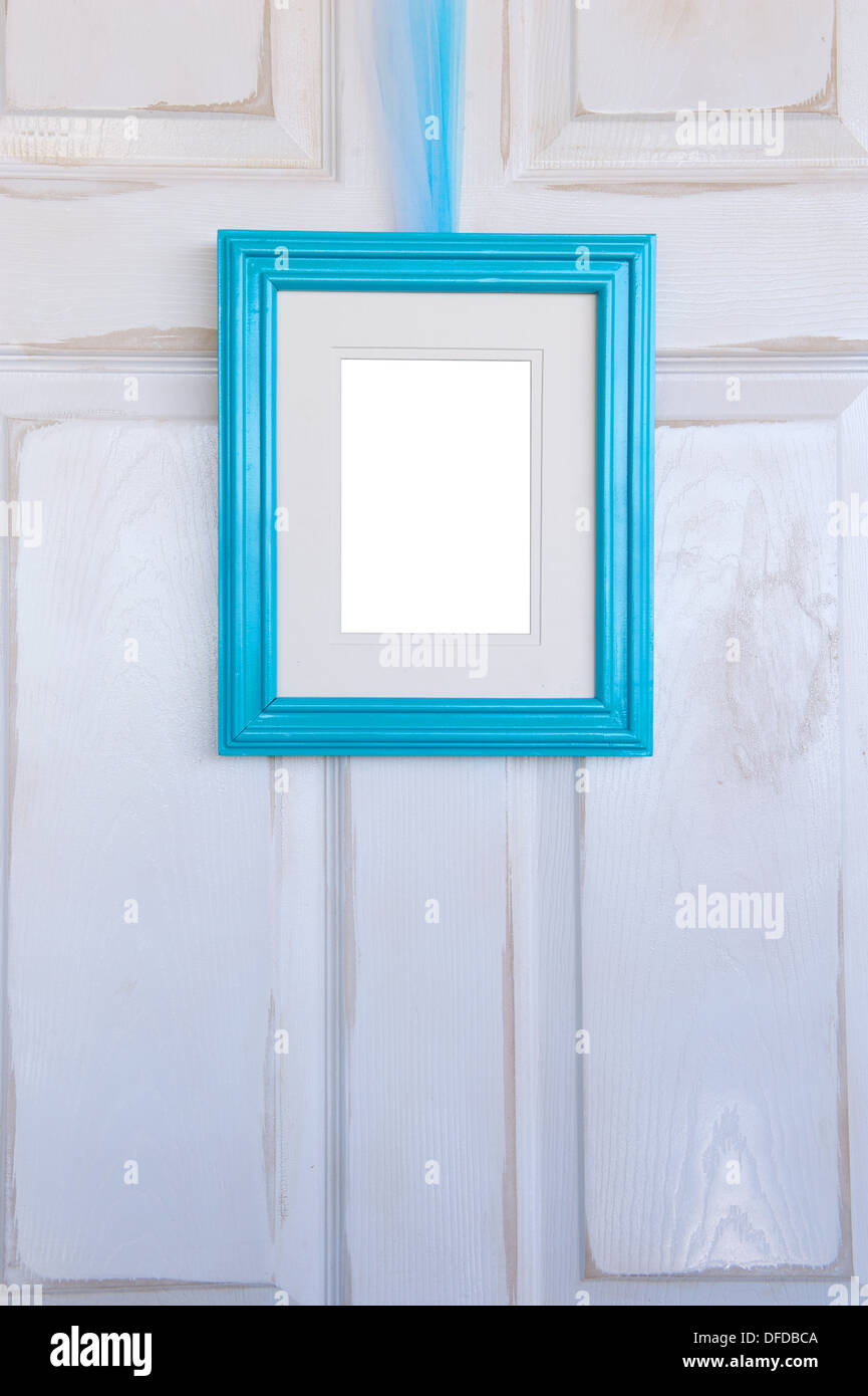 Distressed white door with a blank, turquoise picture frame hanging on ...