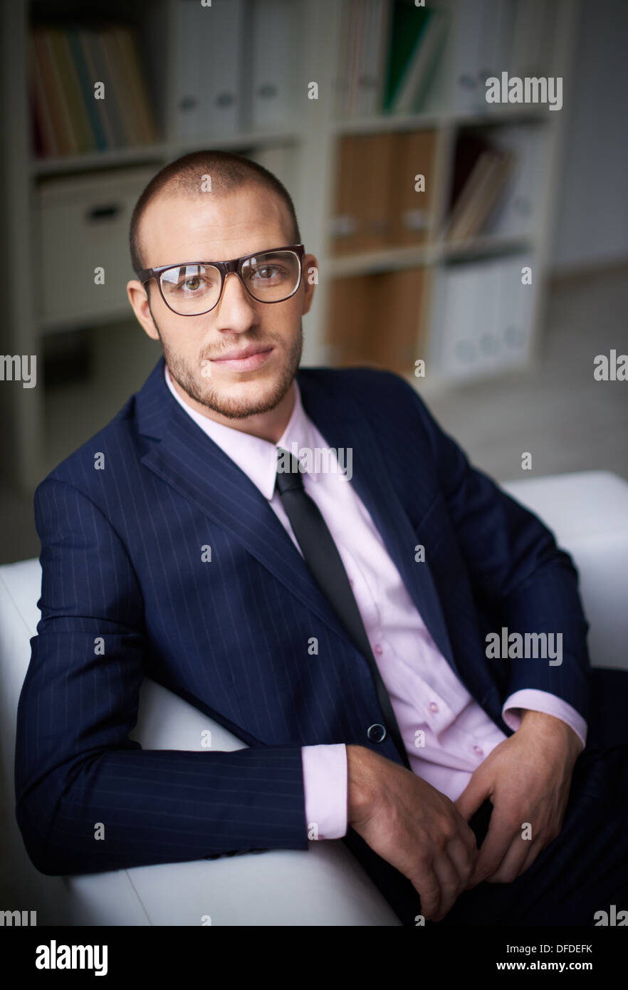 Portrait of attractive male in suit and eyeglasses looking at camera in ...