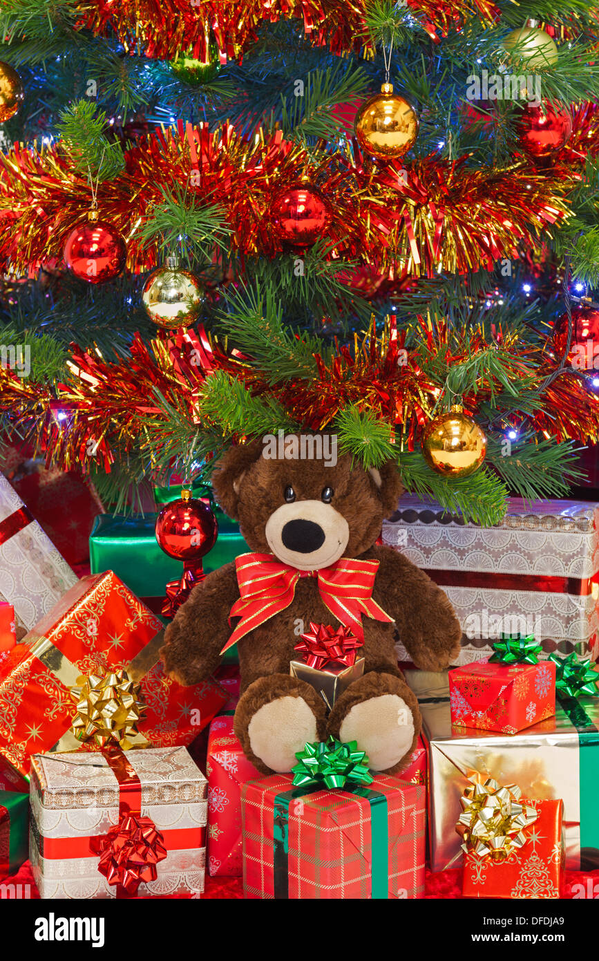 A handmade teddy bear wearing a bow in amongst gifts under a Christmas ...
