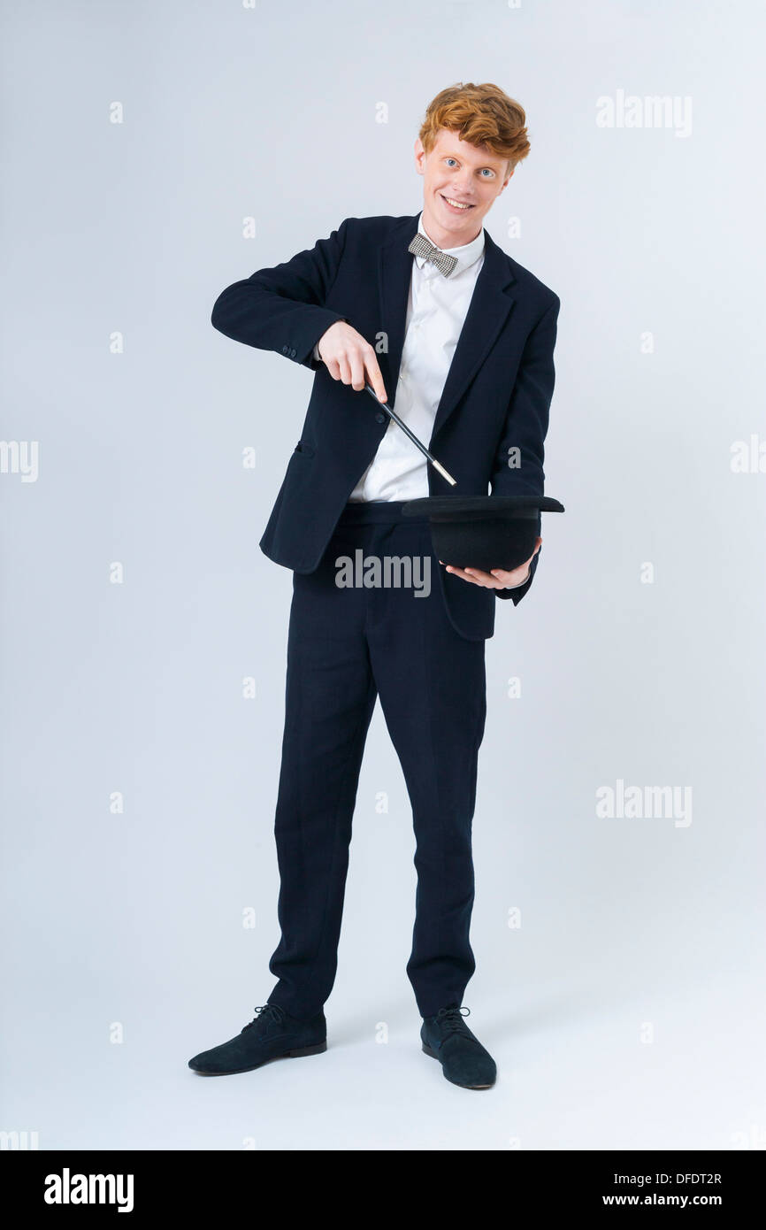 Portrait of young man showing magic with hat, smiling Stock Photo - Alamy