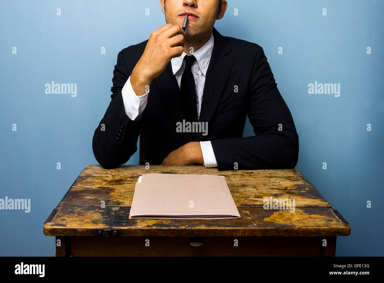 Businessman is sitting at desk and thinking Stock Photo - Alamy