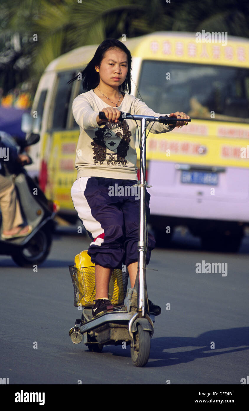 Young girl riding an electric scooter, Jinghong, Xishuangbanna, Yunnan ...