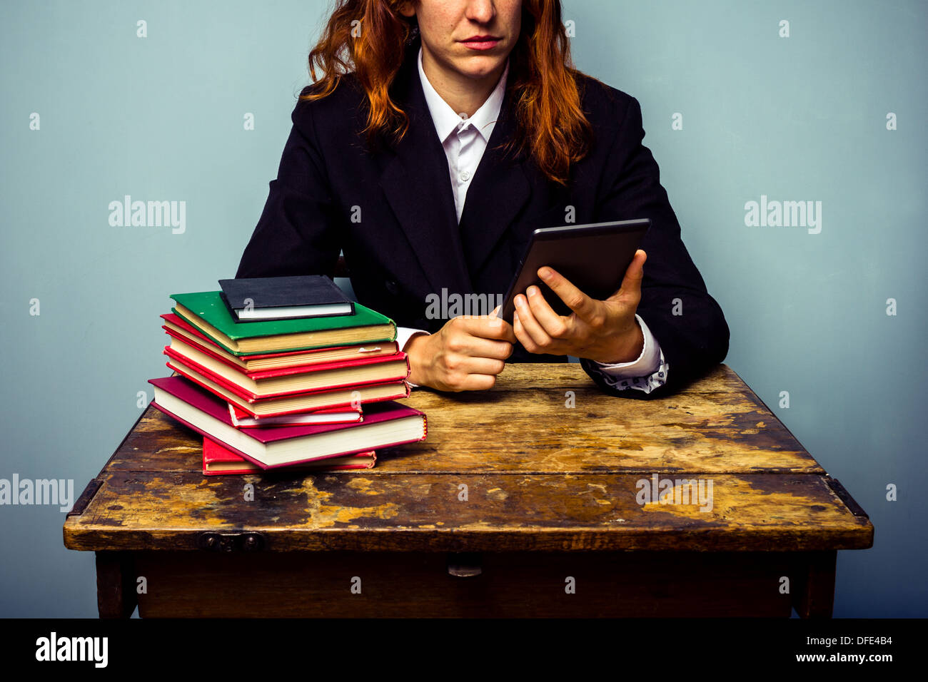 Young businesswoman is sitting at an old desk with a stack books and ...