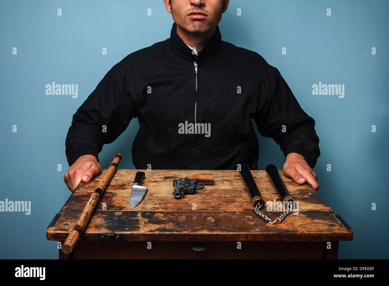 Dangerous criminal at table with weapons laid out in front of him Stock ...