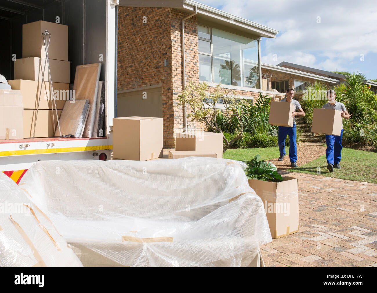 Movers carrying cardboard boxes from house to moving van Stock Photo ...