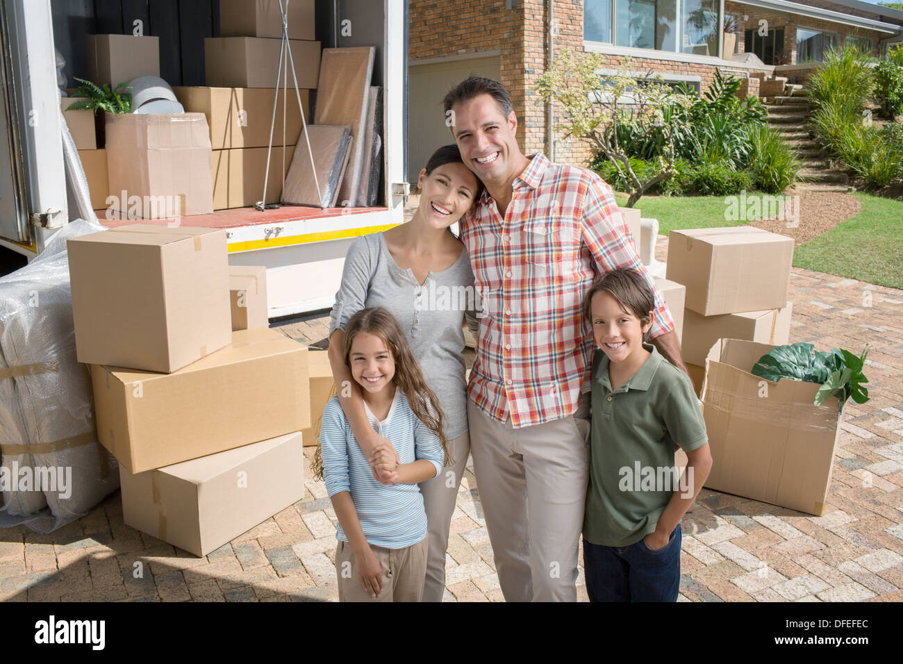Portrait of smiling family standing near moving van in driveway Stock ...