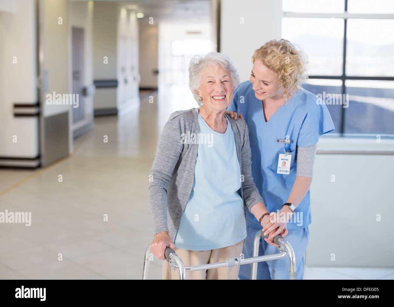 Nurse helping senior patient with walker in hospital corridor Stock ...