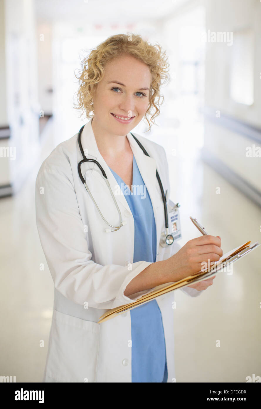 Doctor writing on clipboard in hospital corridor Stock Photo - Alamy