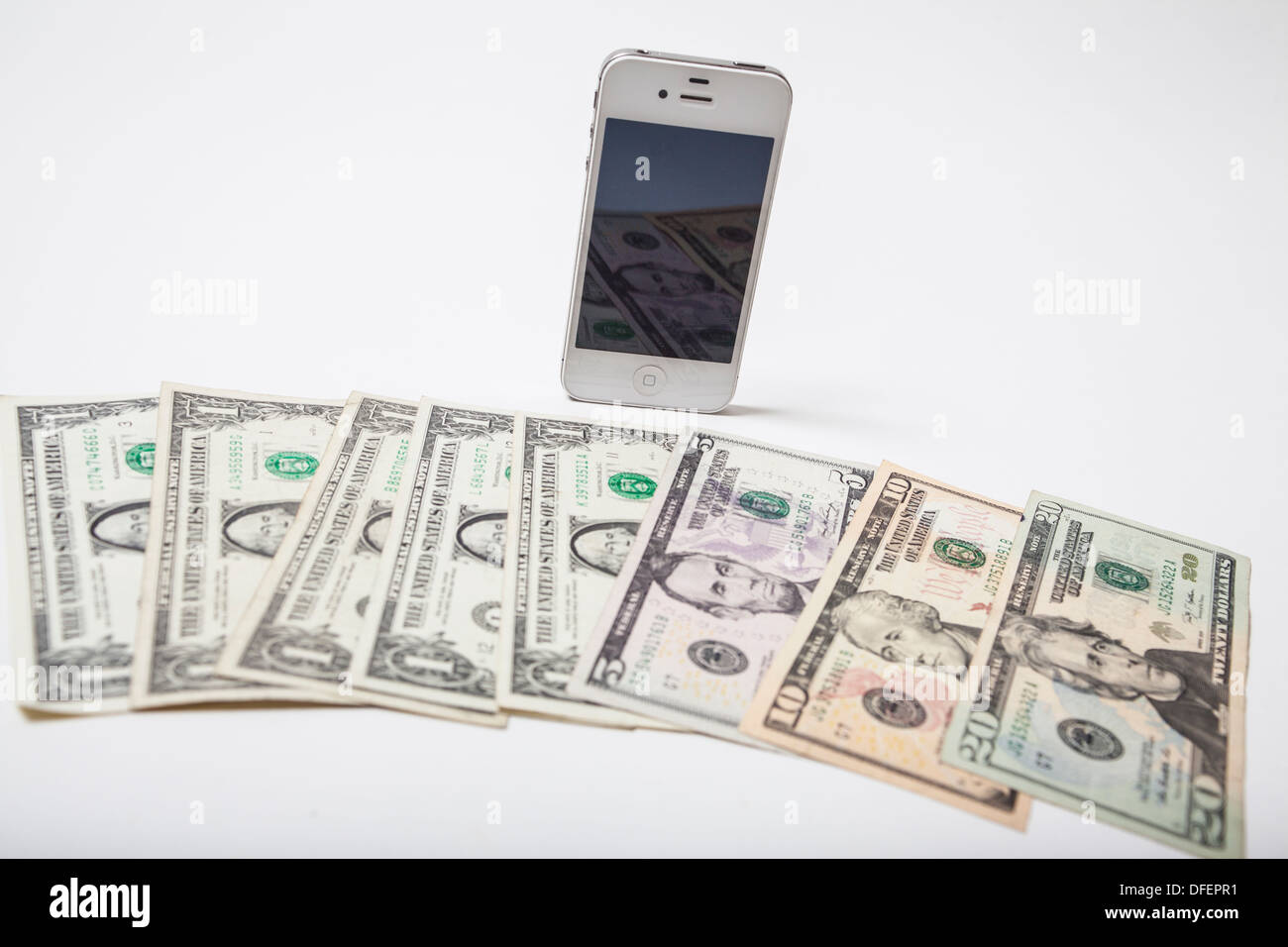 Cash for your iphone. U.S. currency and a used iphone on a white ...