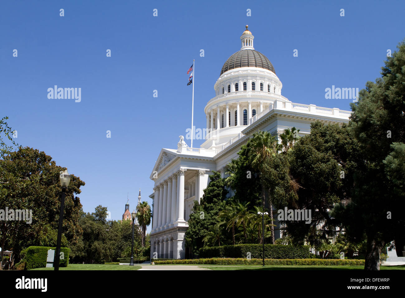 California state capitol and grounds with flags against a blue sky ...