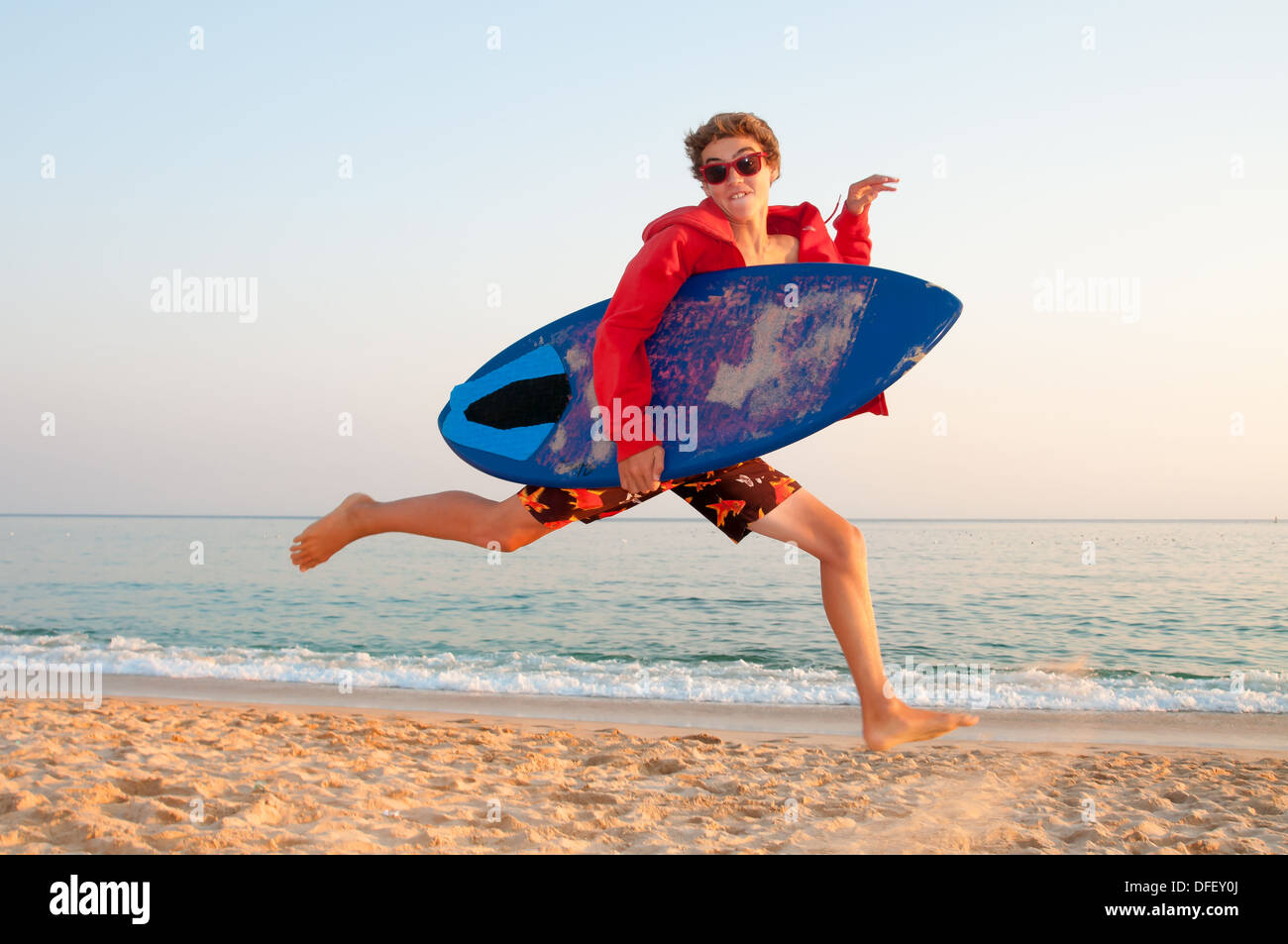 Handsome teen jumping in the beach with skimming board Stock Photo - Alamy