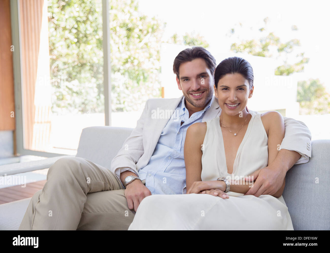 Smiling couple sitting on the couch using tablet pc and watching tv at ...