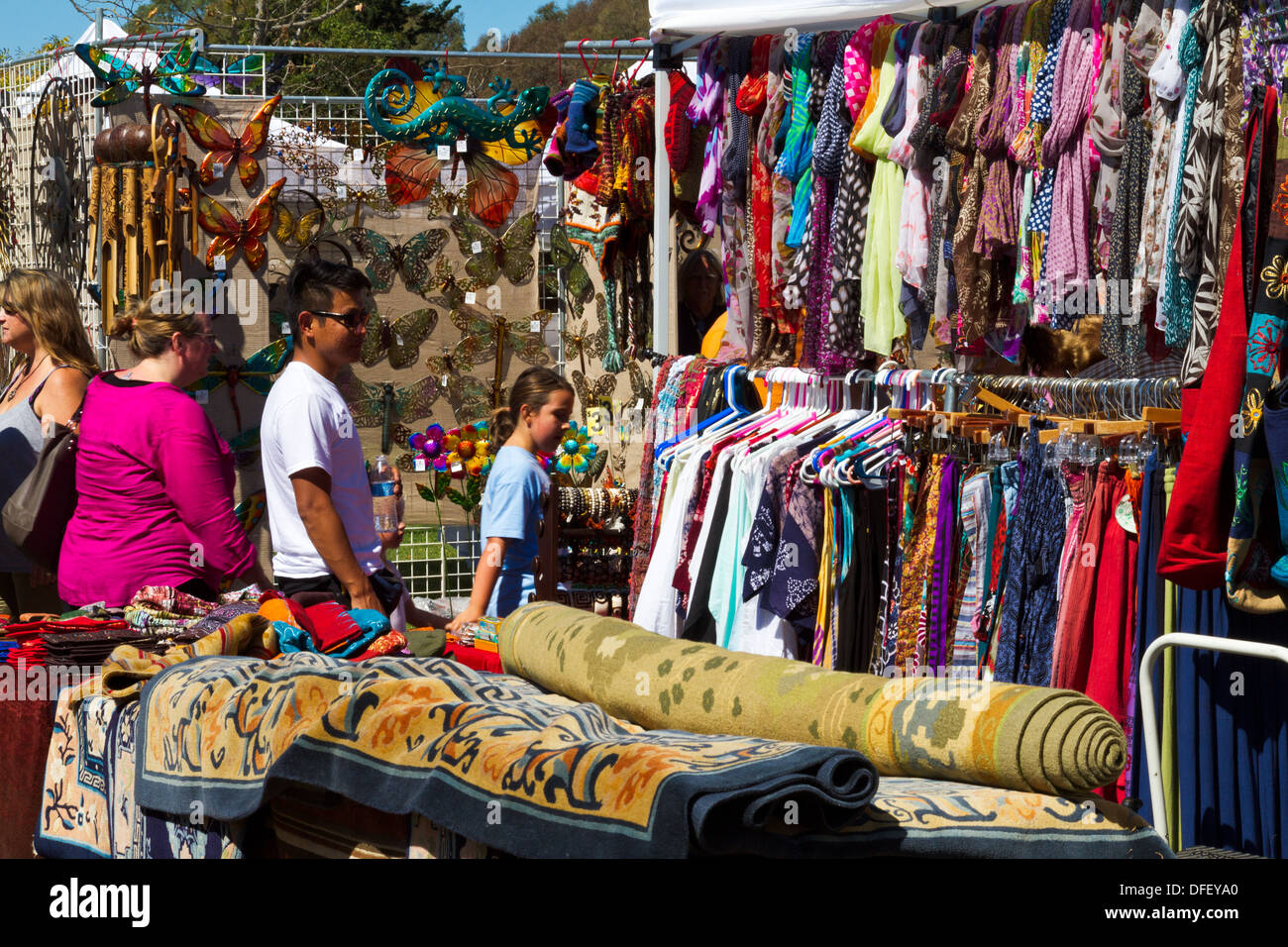 Shoppers strolling through an outdoor bazaar displaying colorful items ...