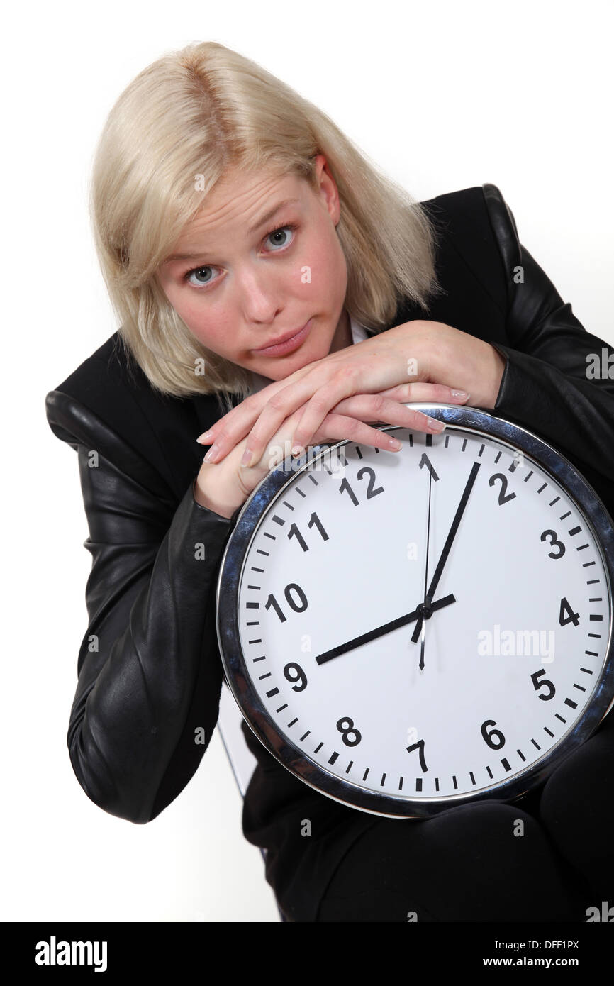 Blond businesswoman leaning on large clock Stock Photo - Alamy