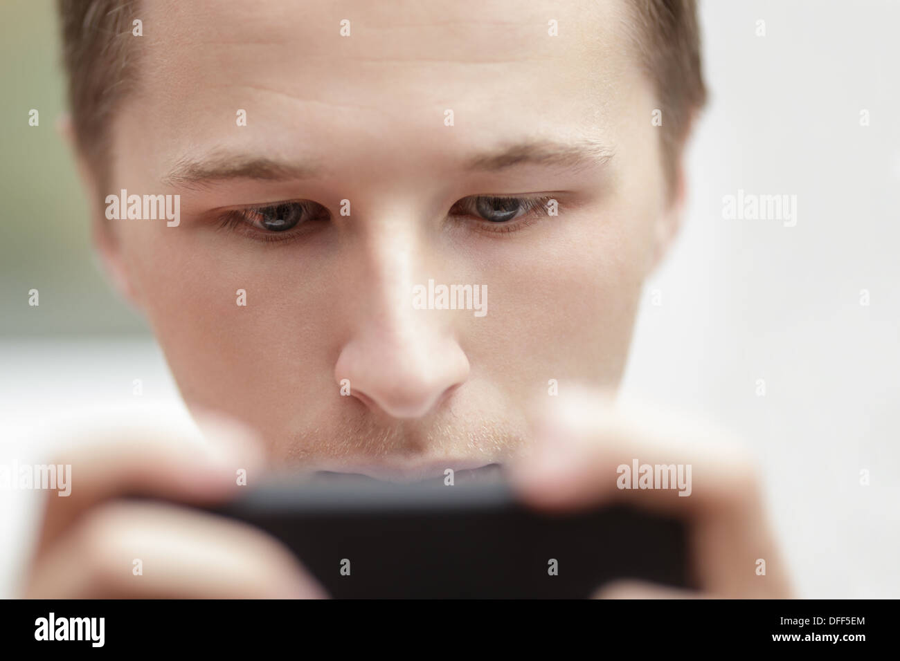 young man looking in the screen of mobile phone, close up portrait ...