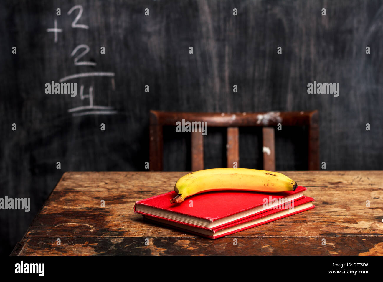 Books and banana on desk in front of blackboard Stock Photo - Alamy