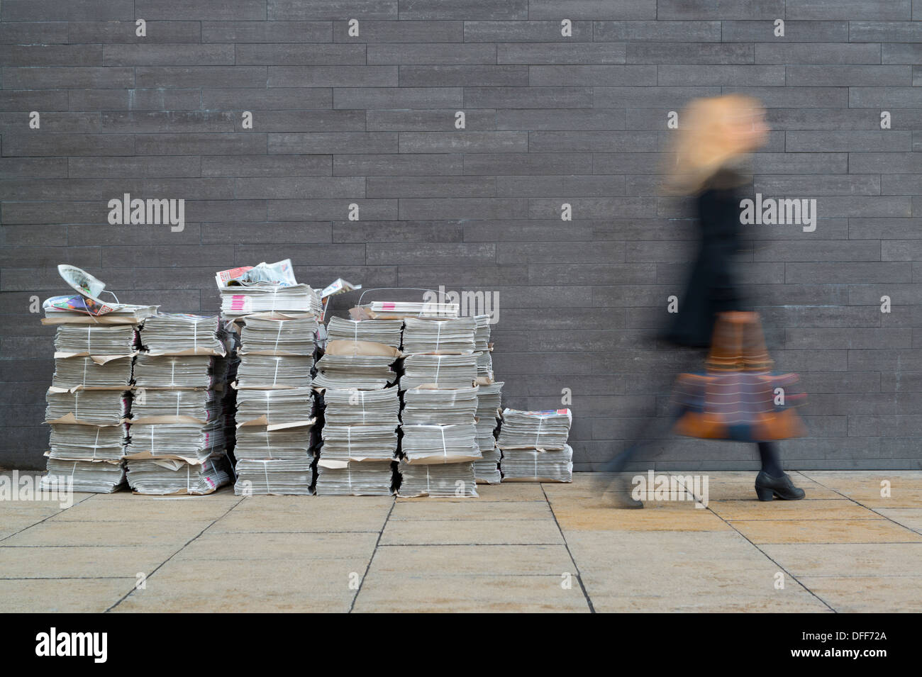 Woman walks past stacks of free Metro newspaper during morning rush ...